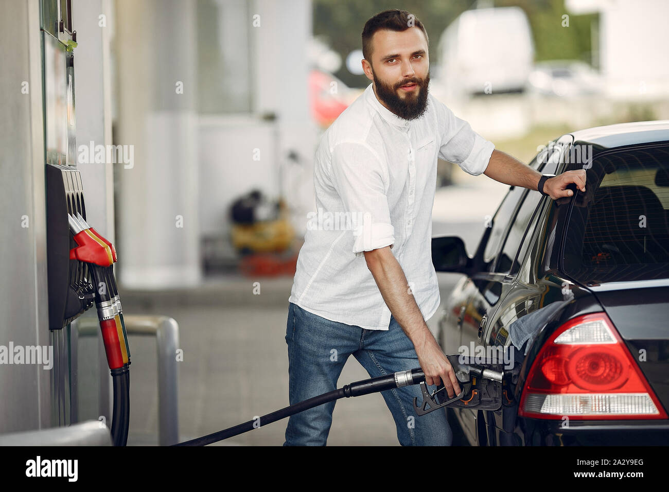 Man on a gas station. Guy refuelong a car. Male in a white shirt Stock ...