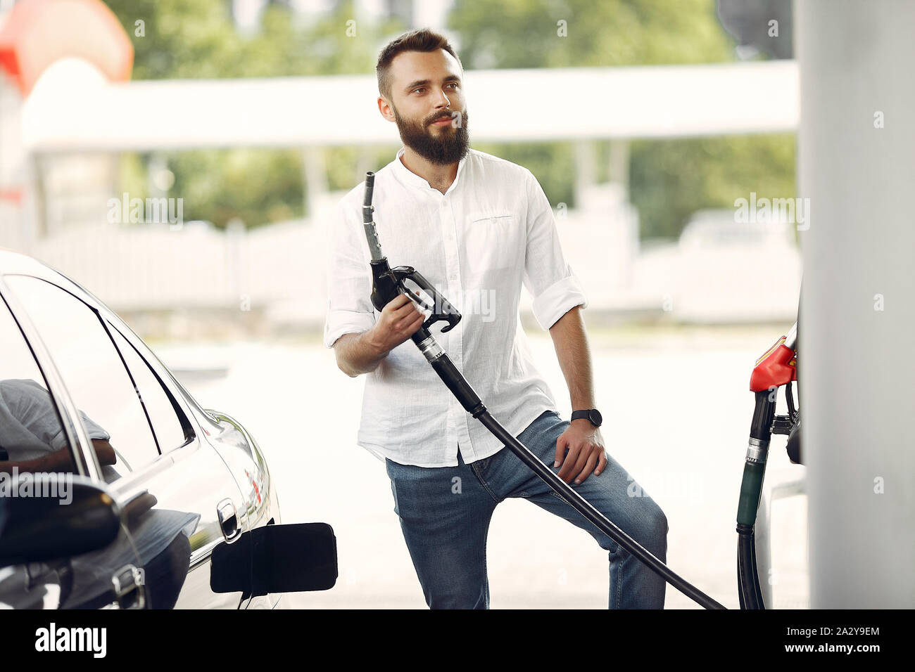 Man on a gas station. Guy refuelong a car. Male in a white shirt Stock ...