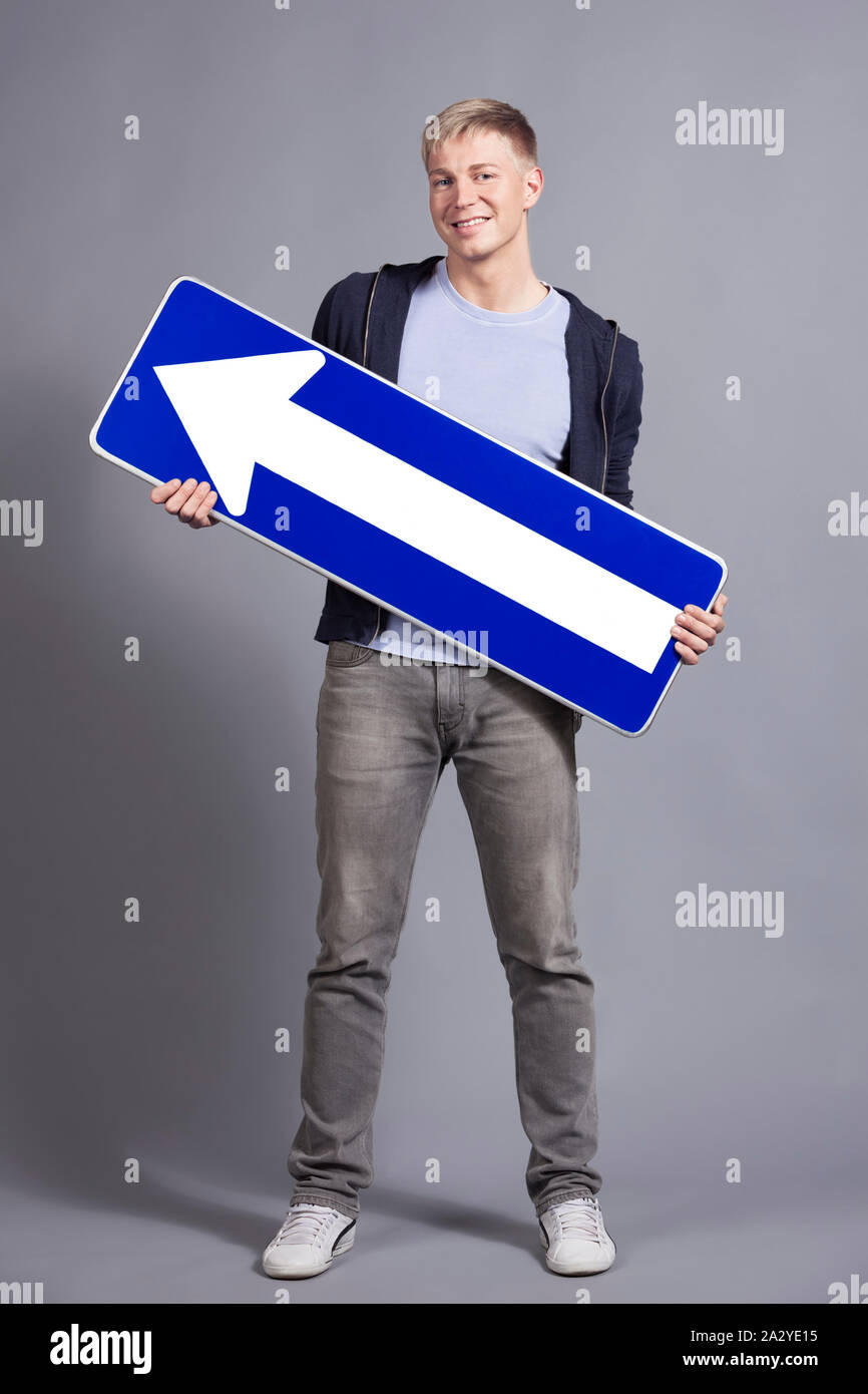 Joyful man holding direction arrow sign Stock Photo - Alamy