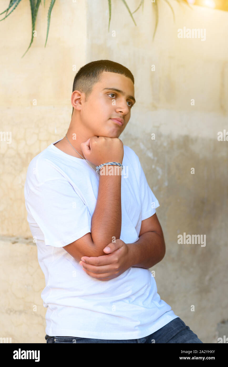 Portrait of cheerful teenager outdoors against a white wall background ...