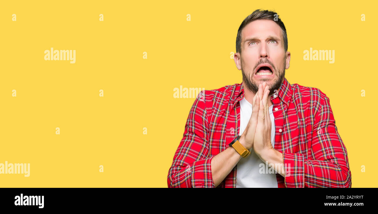 Handsome man wearing casual shirt begging and praying with hands ...