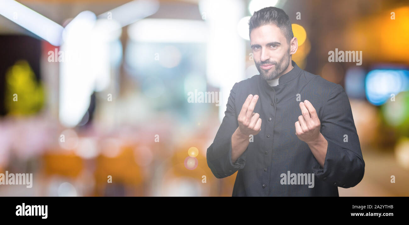 Young Christian priest over isolated background Doing money gesture ...