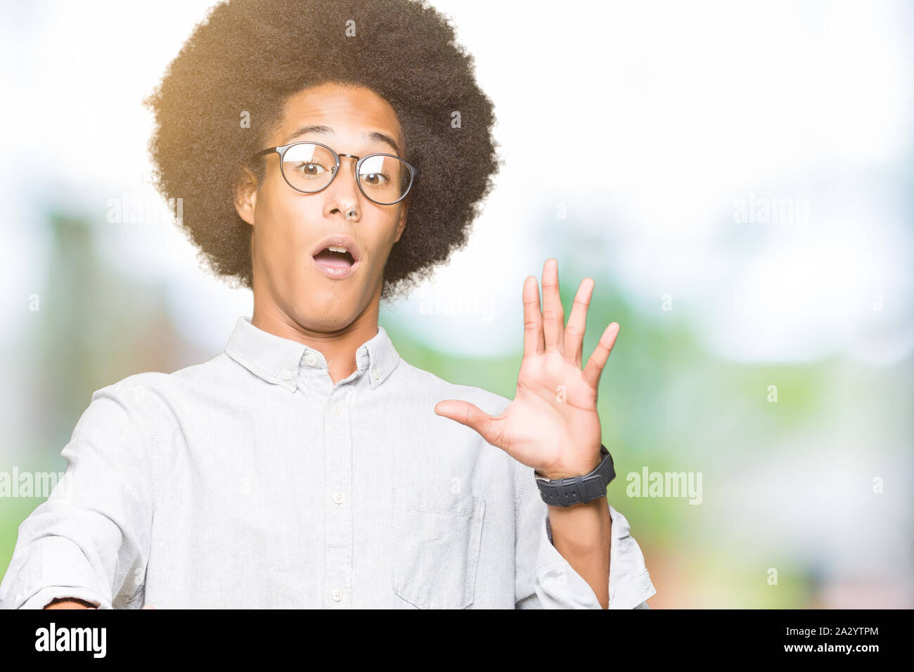 Young african american man with afro hair wearing glasses afraid and ...