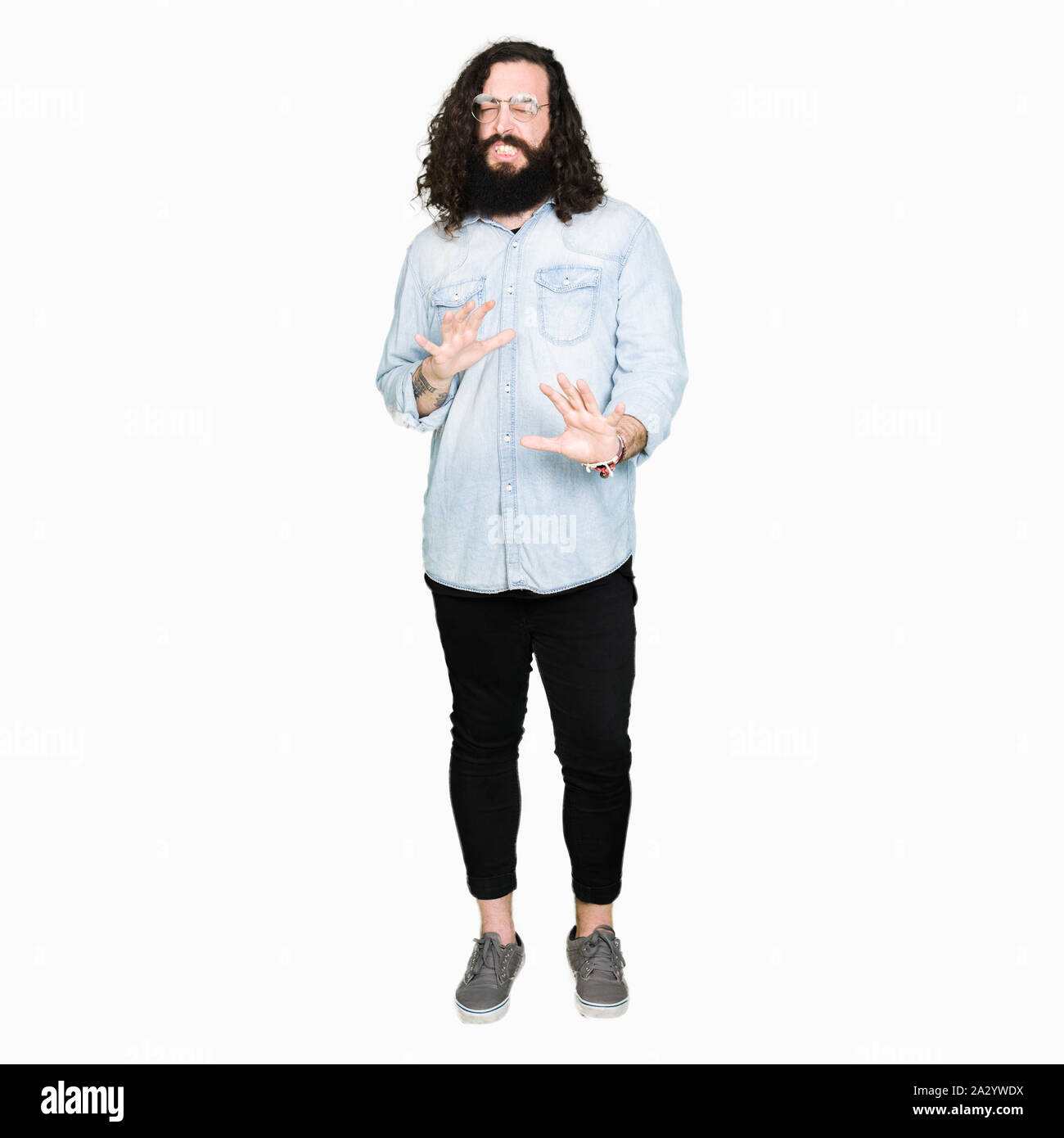 Young hipster man with long hair and beard wearing glasses disgusted ...