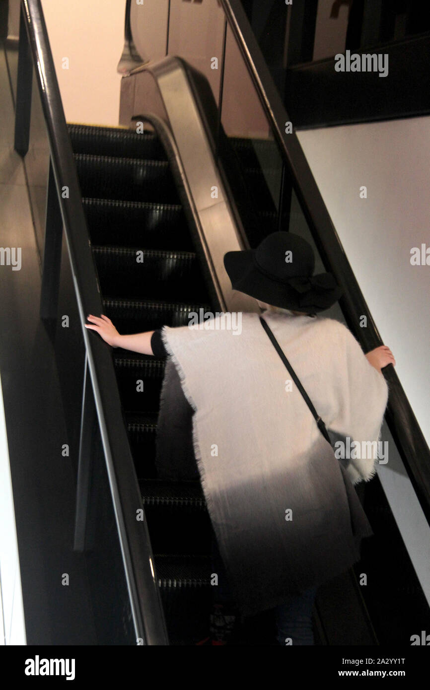 Woman on escalator inside building Stock Photo - Alamy
