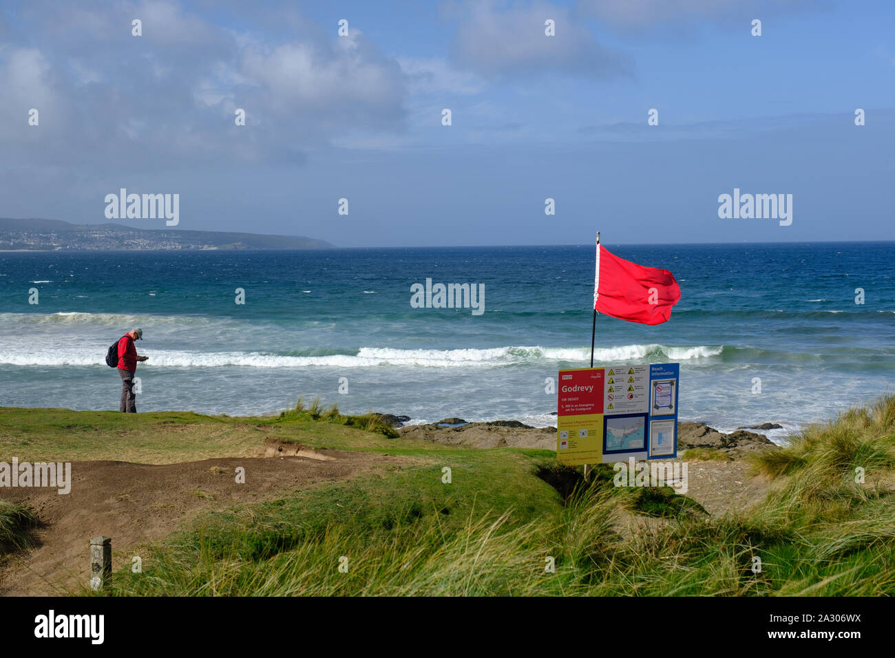 A red RNLI Lifeguards warning flag flying above the beach at Godrevy in ...