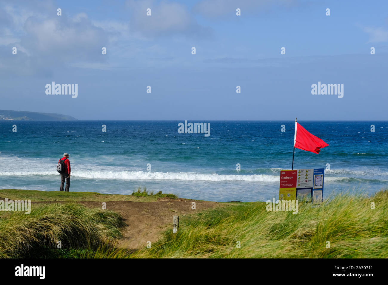 A red RNLI Lifeguards warning flag flying above the beach at Godrevy in ...