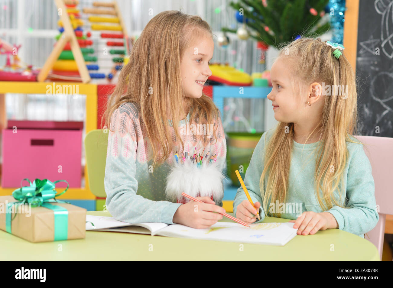 Portrait of cute little sisters drawing with pencils Stock Photo - Alamy