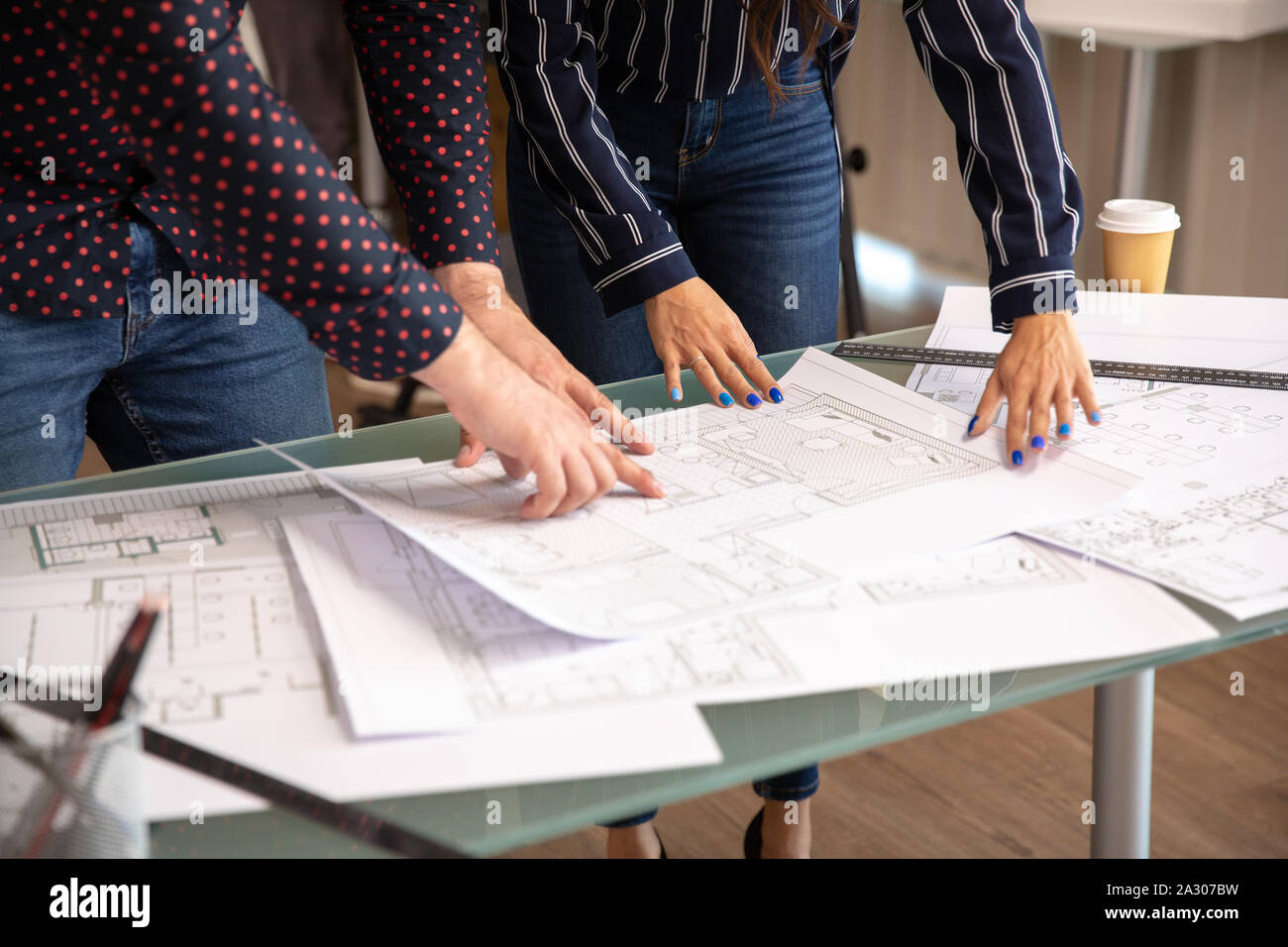 Close up of two architects hands pointing at some drawings. Young ...