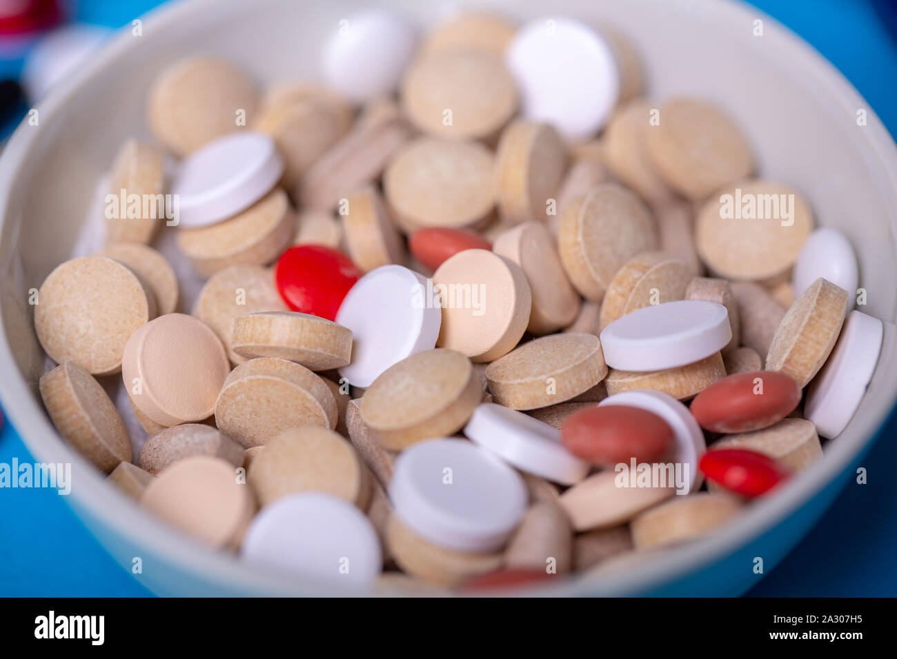 Close up with a bowl of pills of different colors. Macro and blue ...