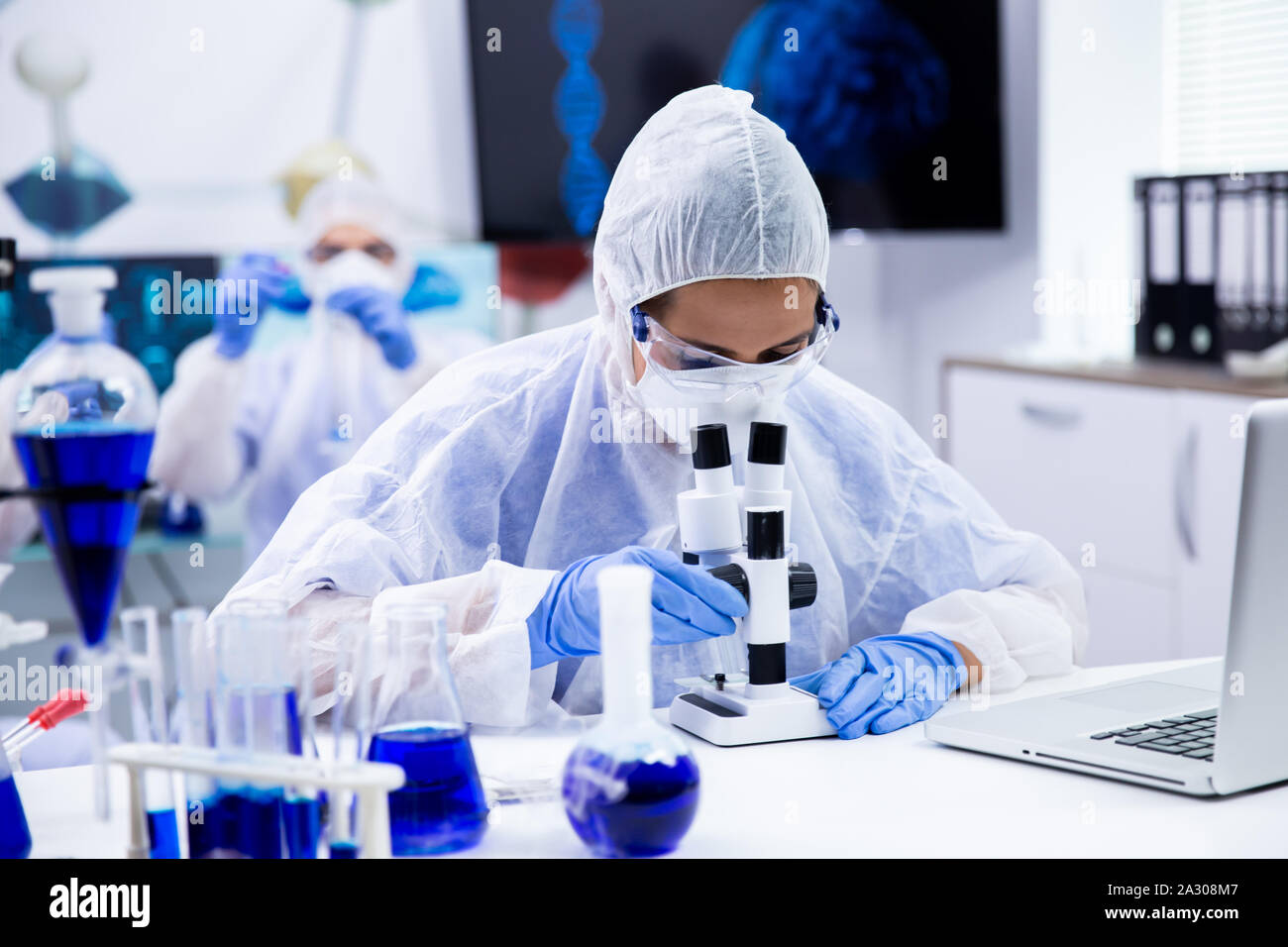 Female scientist looking through a microscope in research laboratory ...