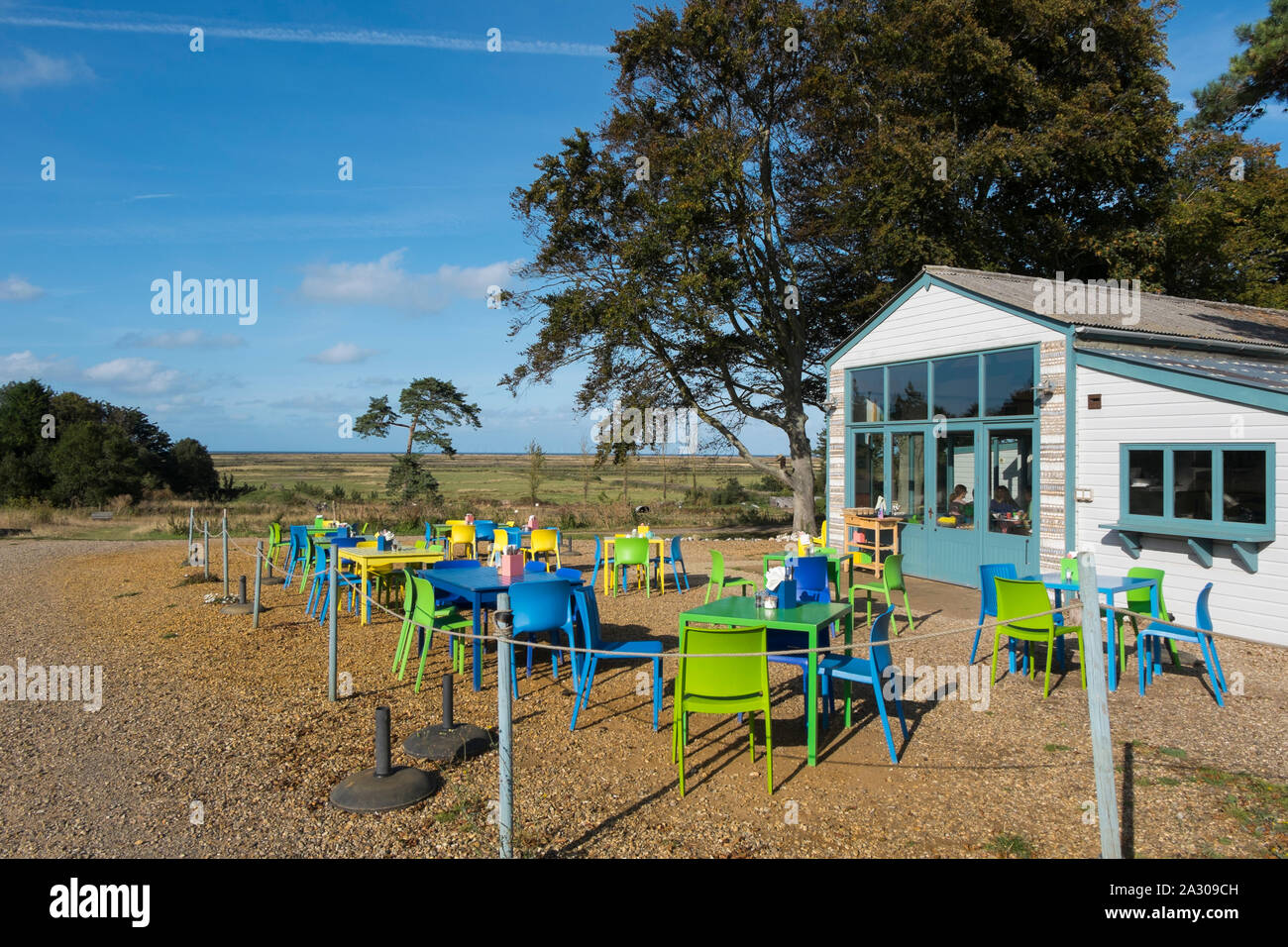 Blue, green and yellow chairs and tables outside Wiveton Hall cafe ...