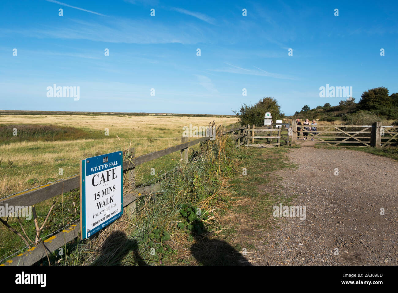 The view across the marshes to the North Sea and a sign to Wiveton Hall ...
