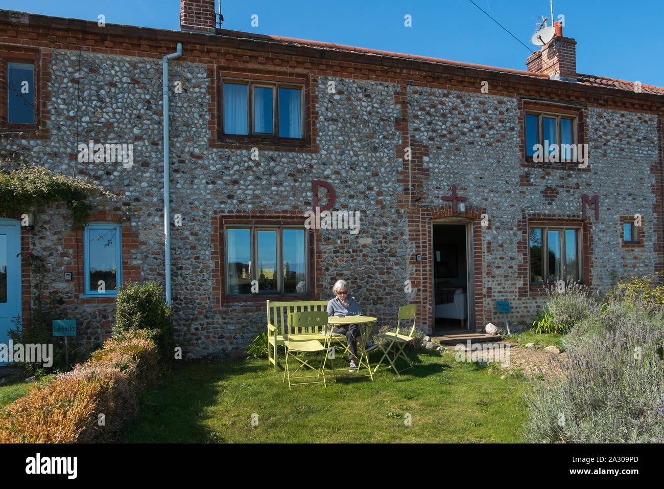Grey haired grandmother sitting on a bench reading a magazine outside ...