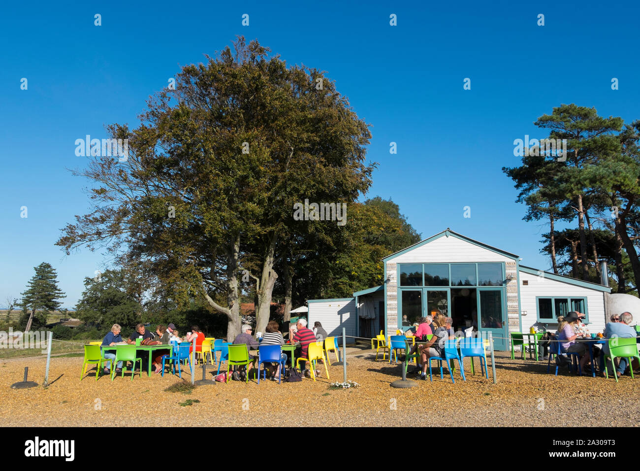 People having lunch and tea on blue, green and yellow chairs and tables ...