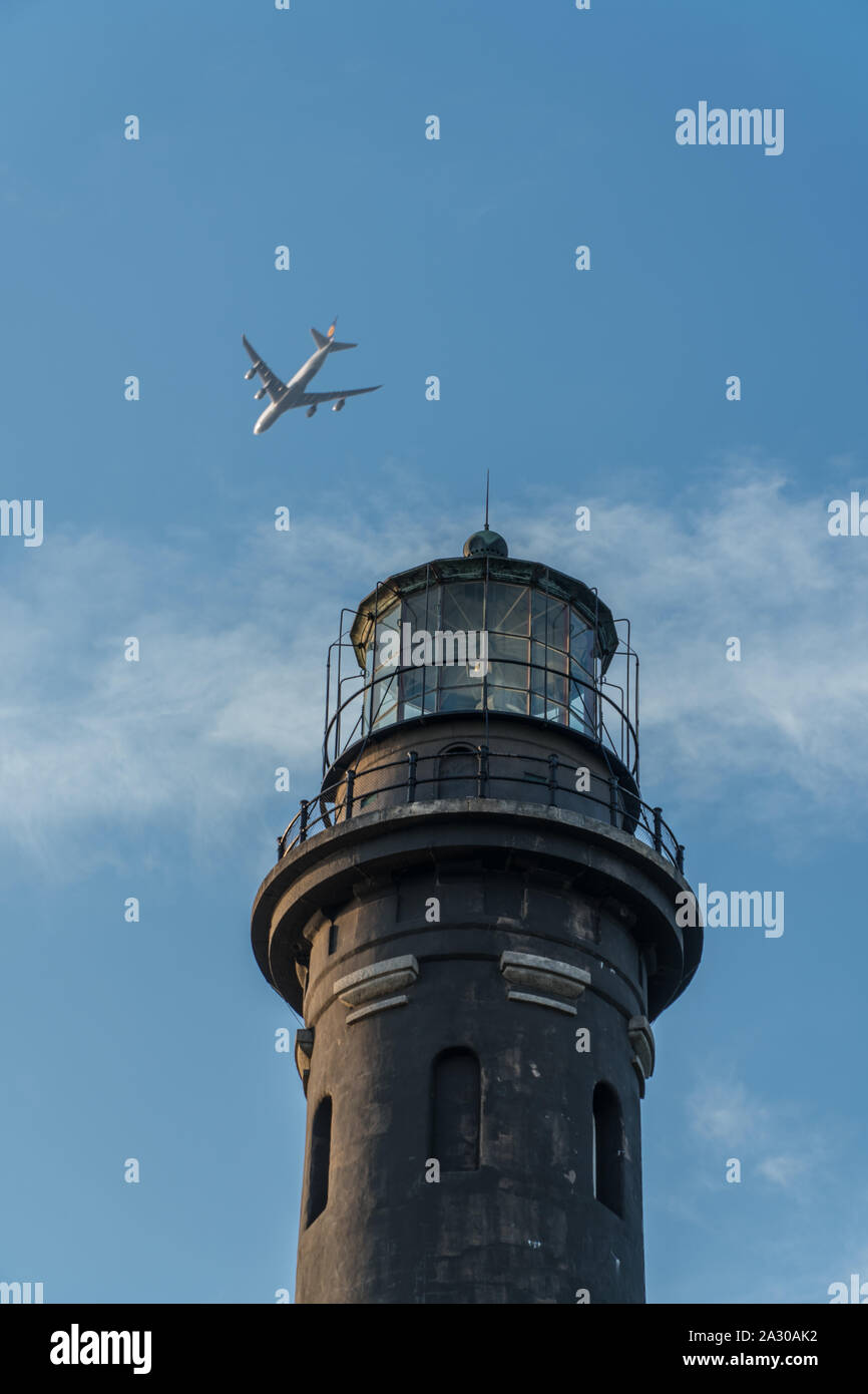 Flying passenger jet airplane passes over lighthouse monument on clear ...