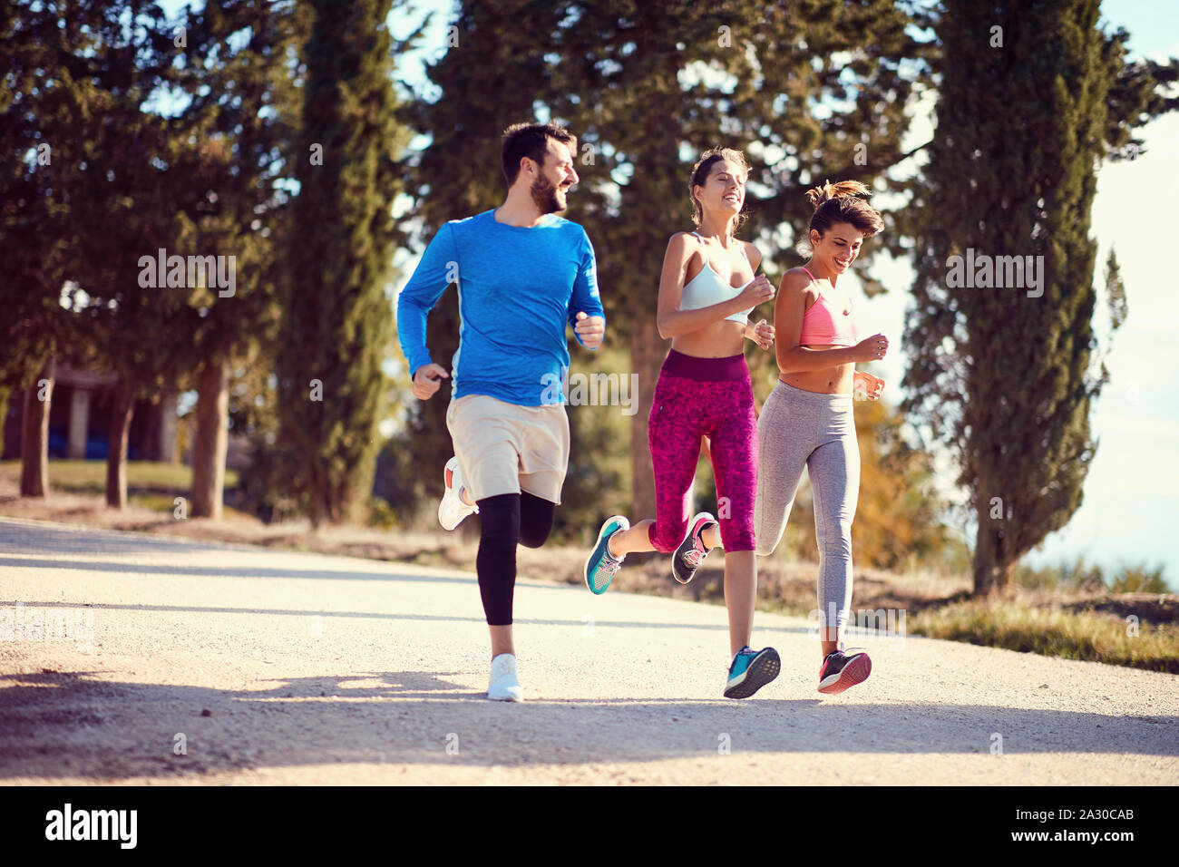 Young smiling friends running together in nature. Young people ...