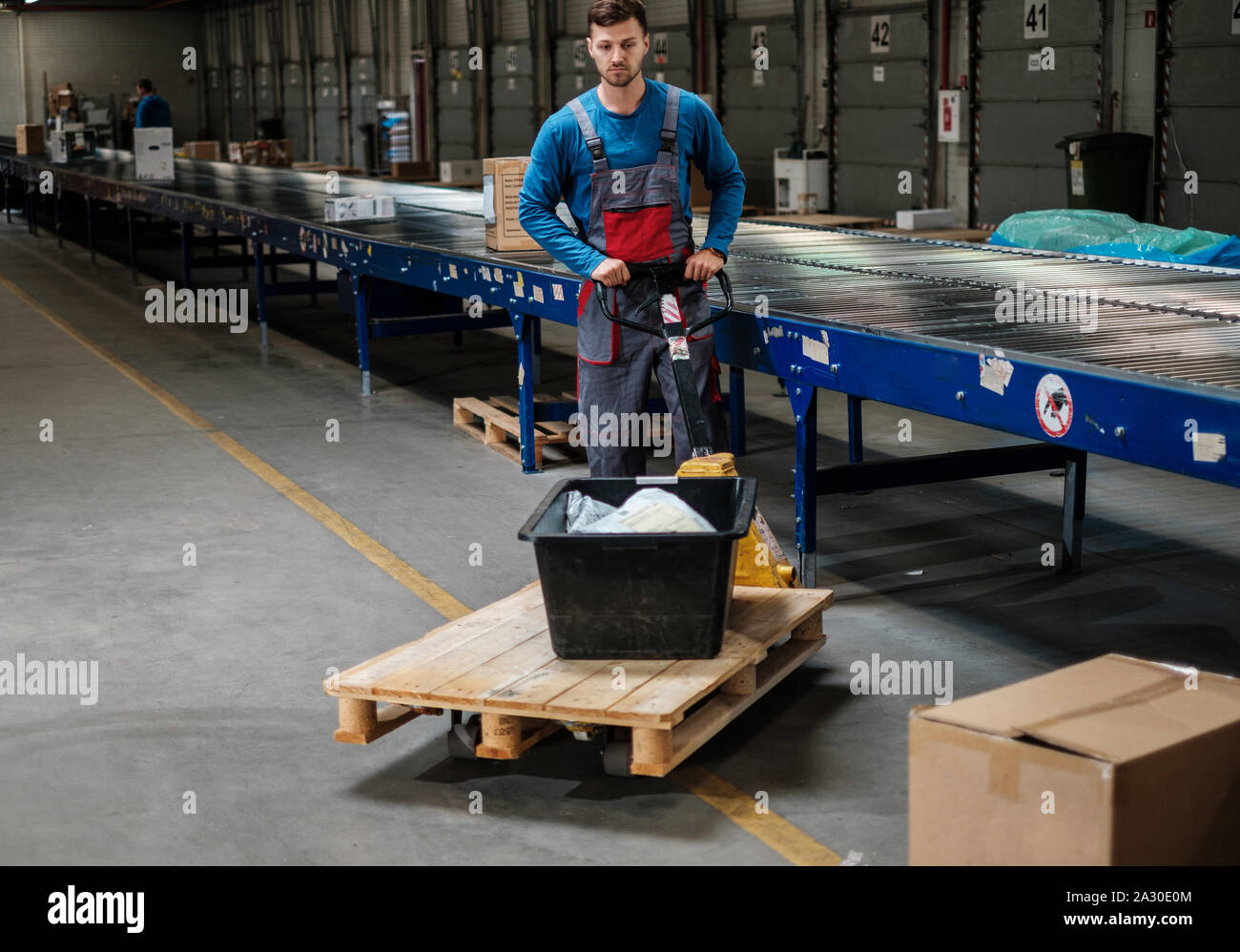 Warehouse worker with a pallet rack Stock Photo - Alamy