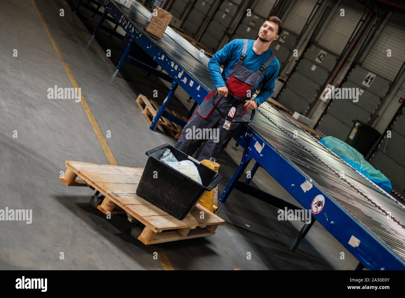 Warehouse worker with a pallet rack Stock Photo - Alamy