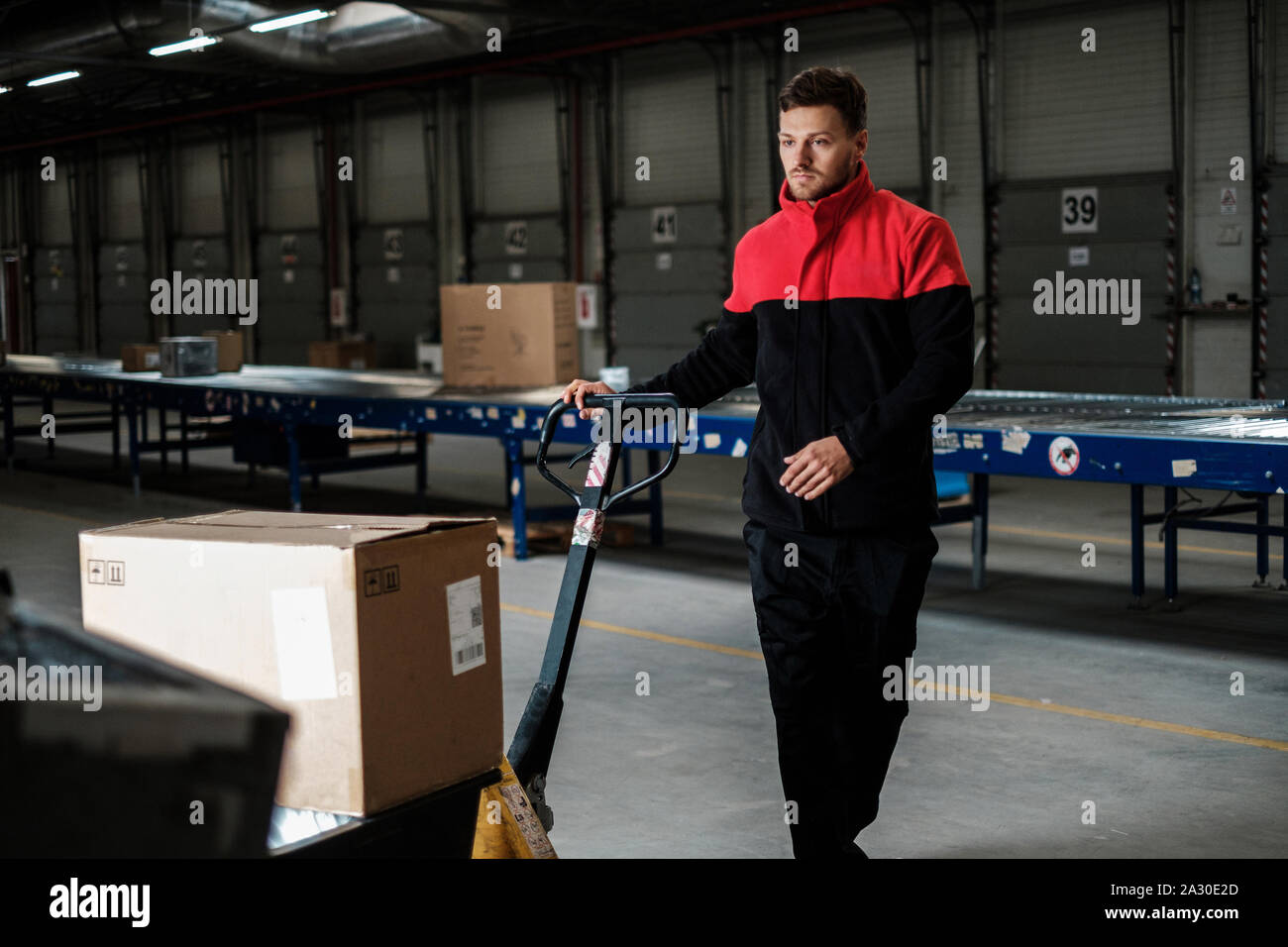 Warehouse worker with a pallet rack Stock Photo - Alamy