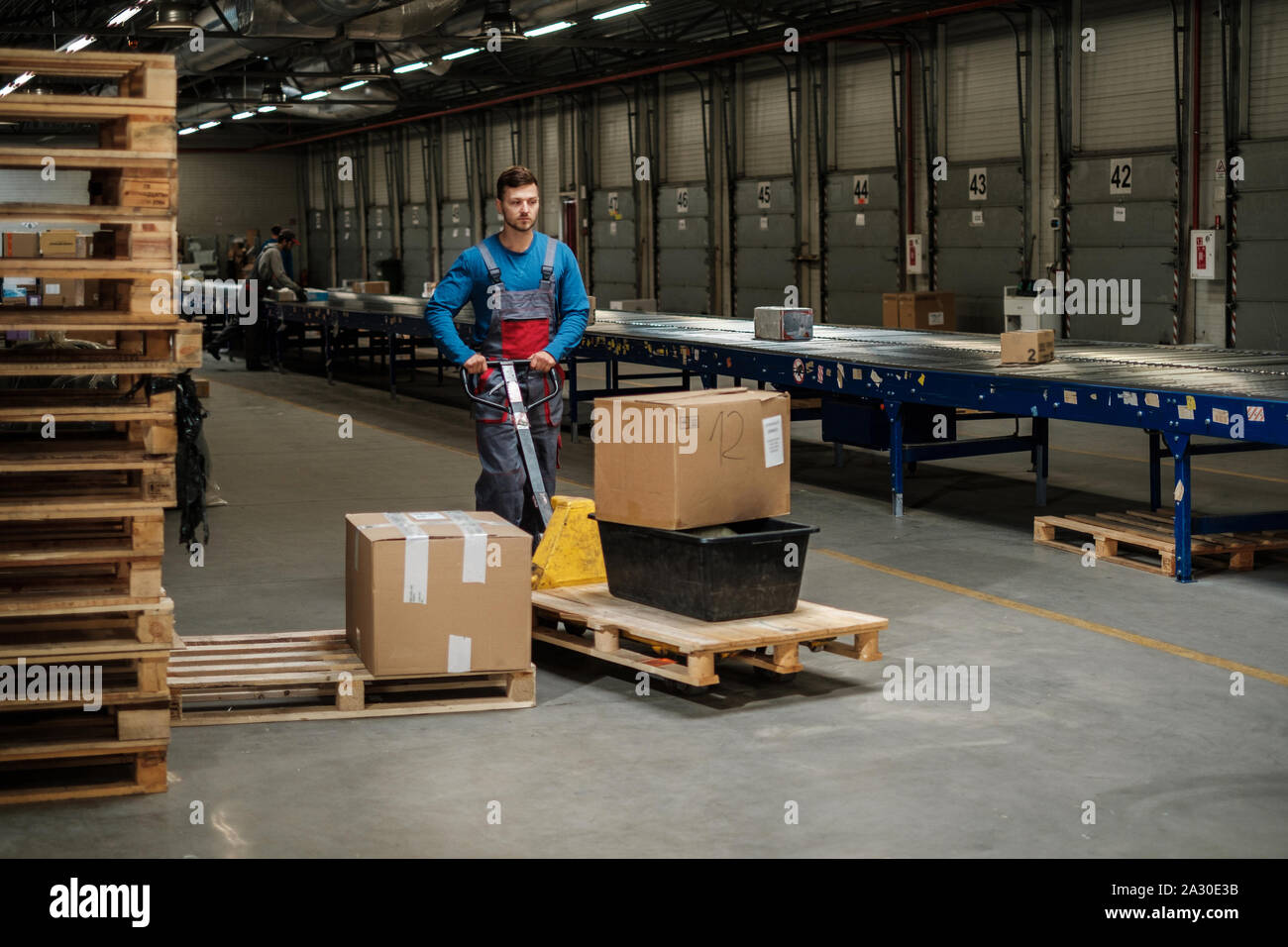 Warehouse worker with a pallet rack Stock Photo - Alamy