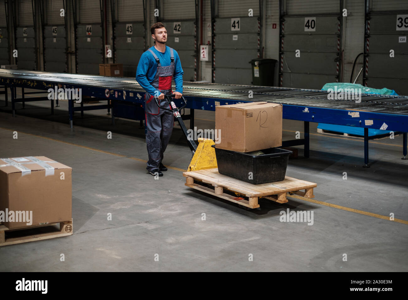Warehouse worker with a pallet rack Stock Photo - Alamy