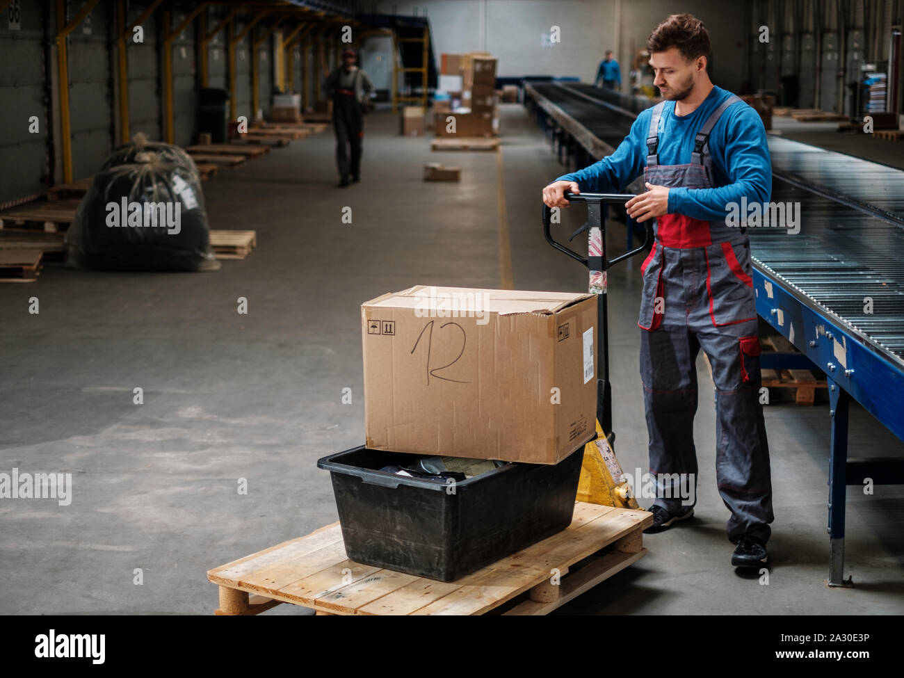 Warehouse worker with a pallet rack Stock Photo - Alamy