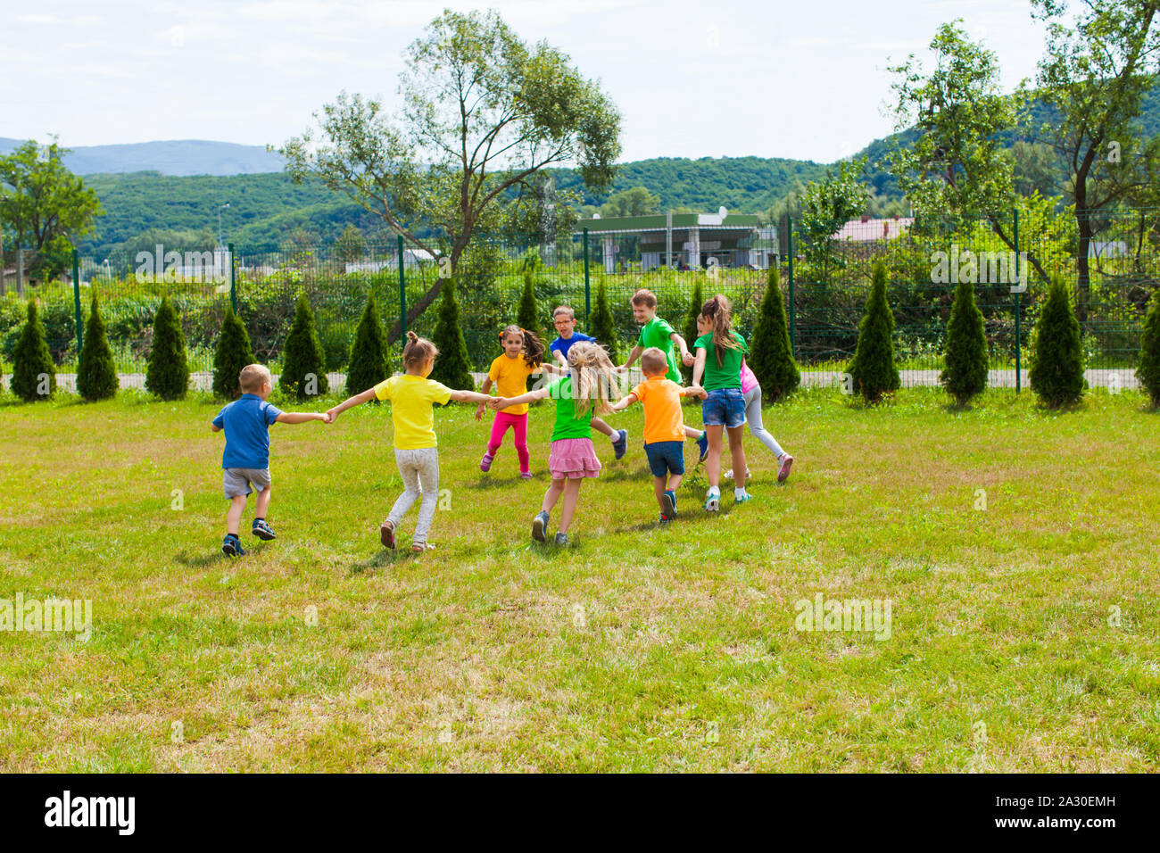 Children run holding hands on the green grass. Train game, fast running ...