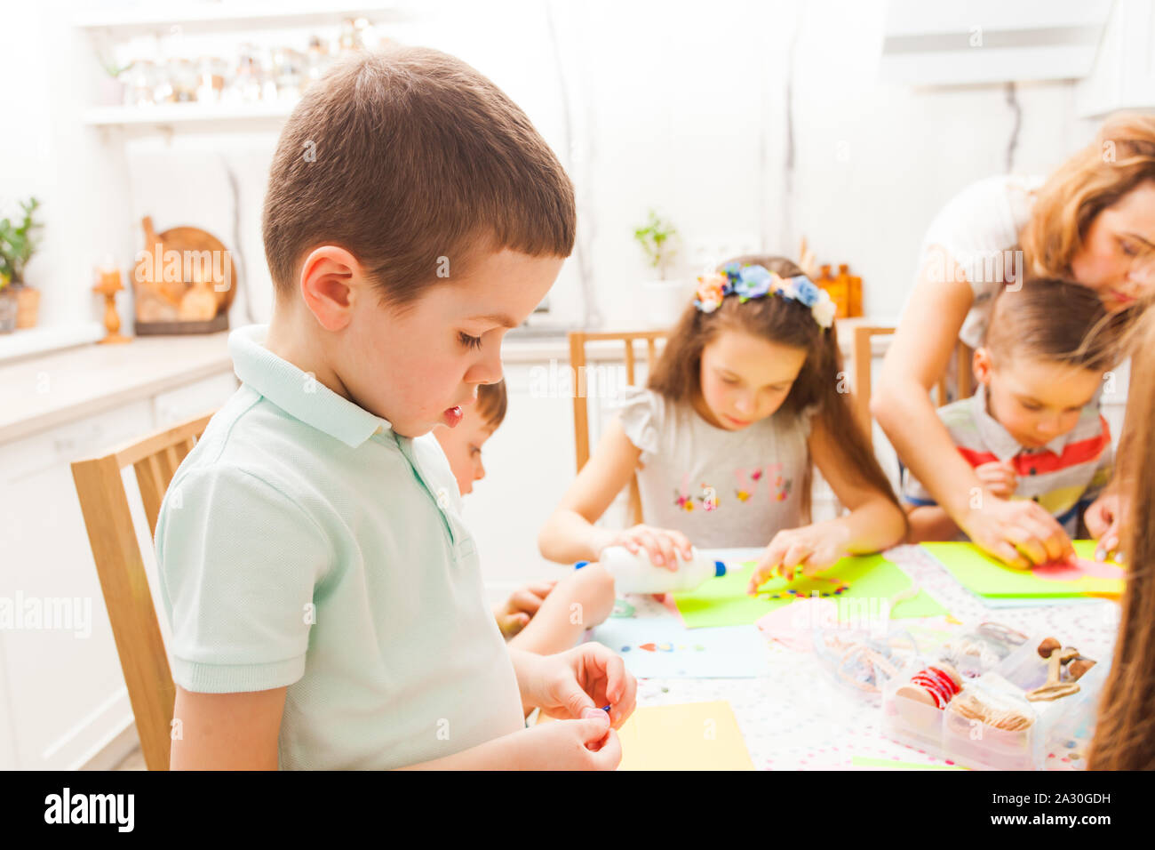 Little boy stand in front of other children and makes a detail for his ...