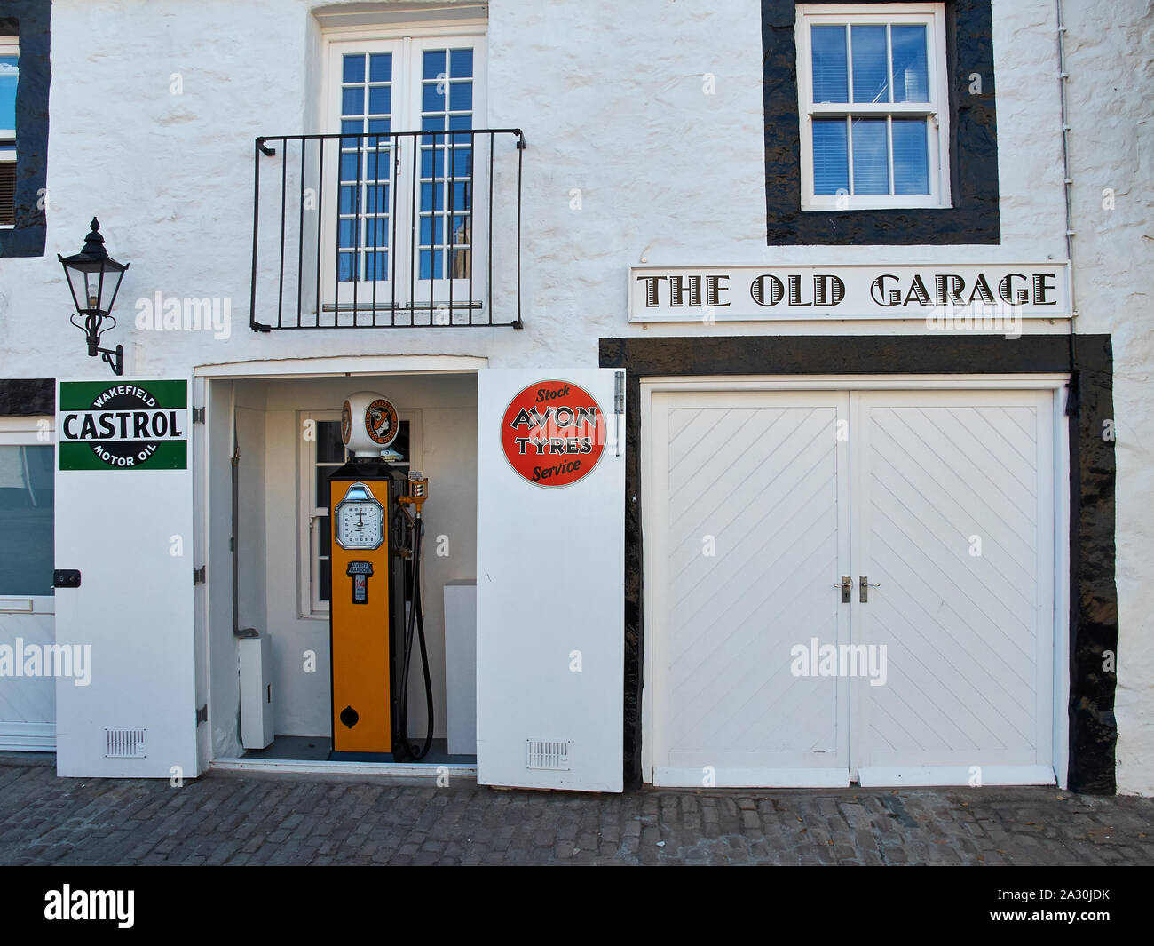 White painted property called 'The Old Garage' with petrol pump ...