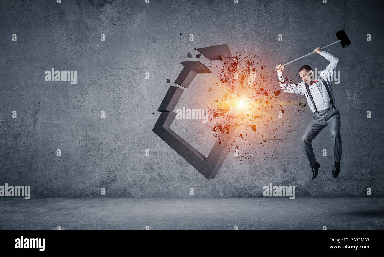 Determined businessman jumping and breaking with hammer house concrete ...