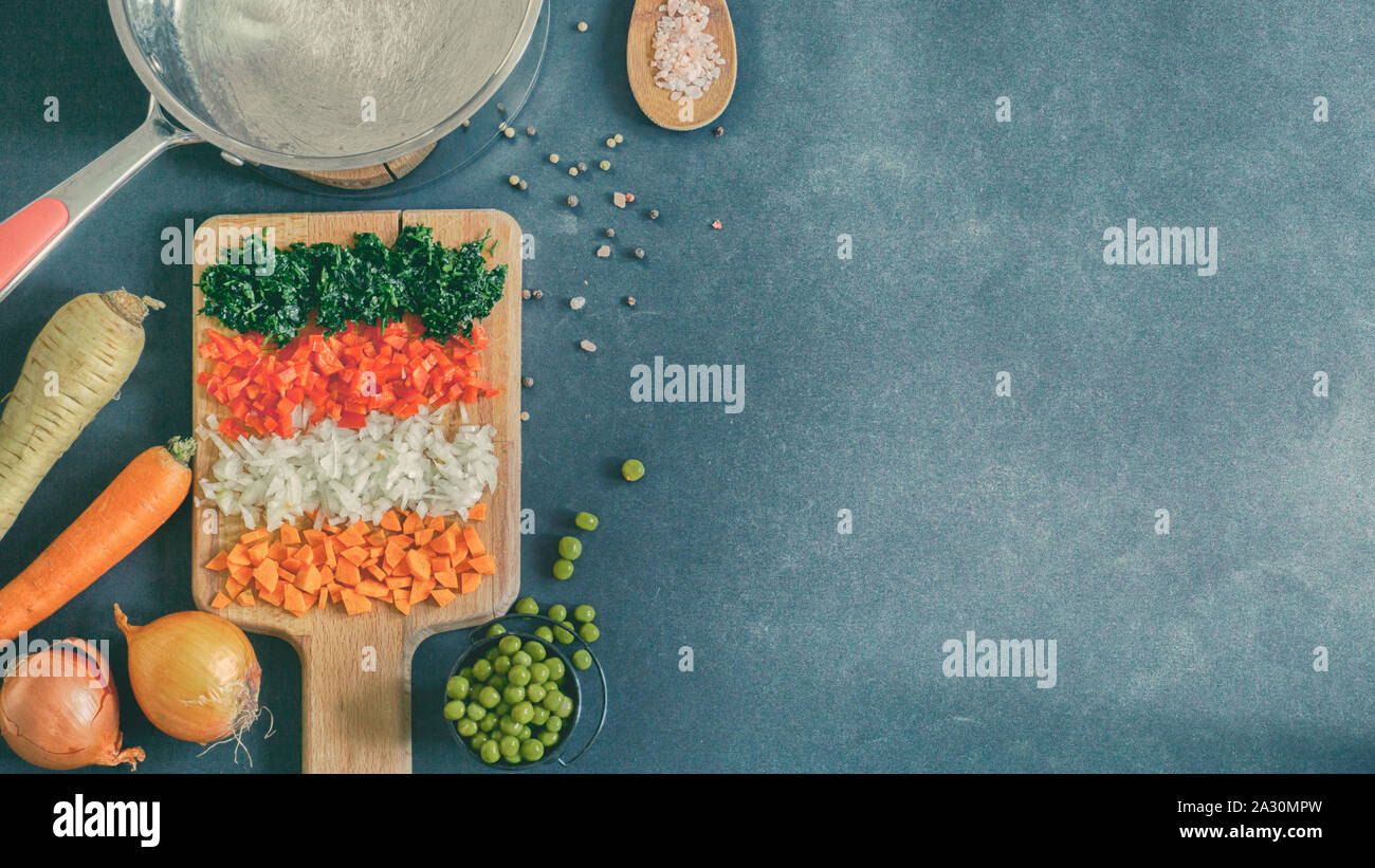 Top view of soup recipe chopped vegetables on wooden chopper on black ...