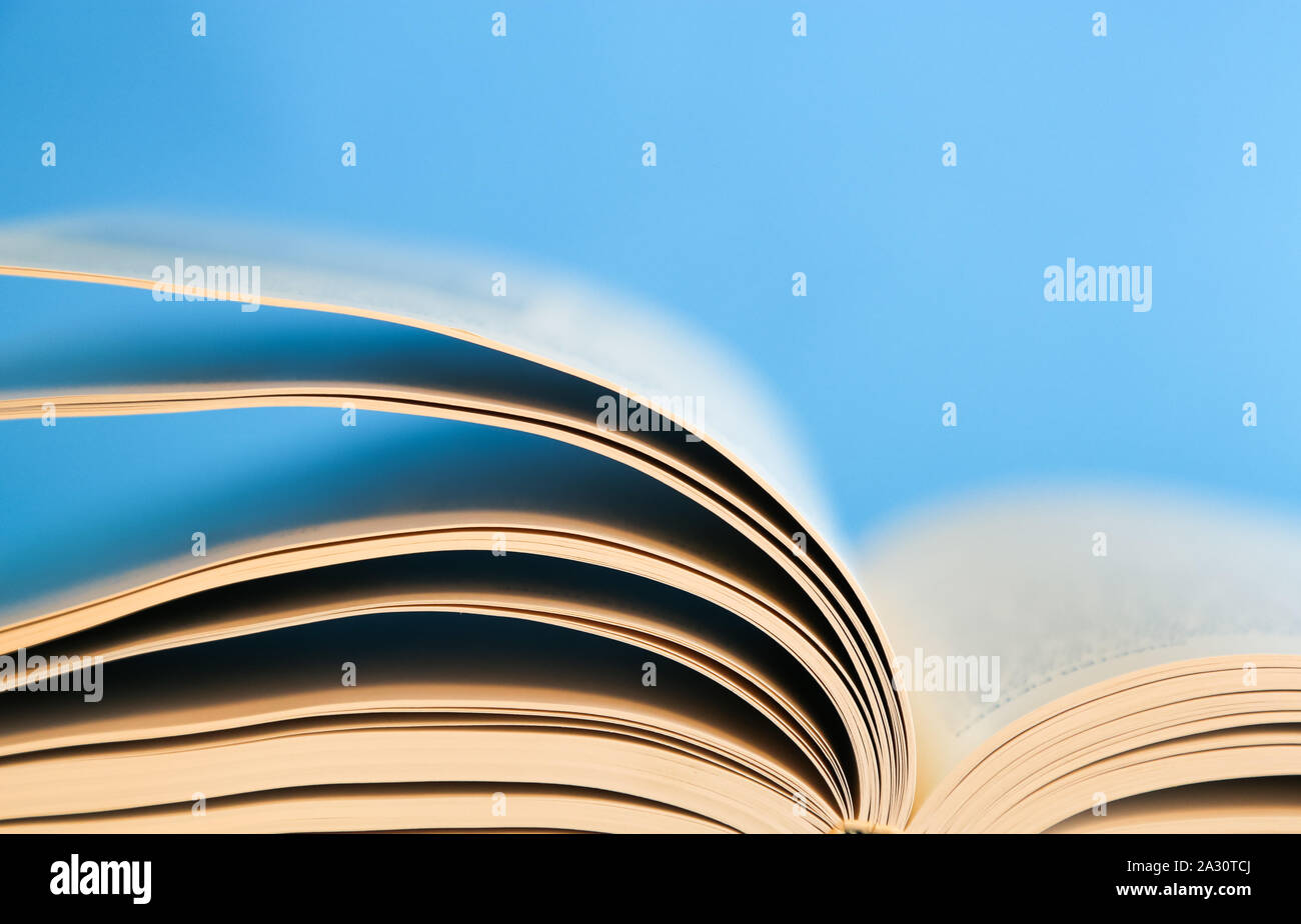 Book over a blue background with pages turning Stock Photo - Alamy