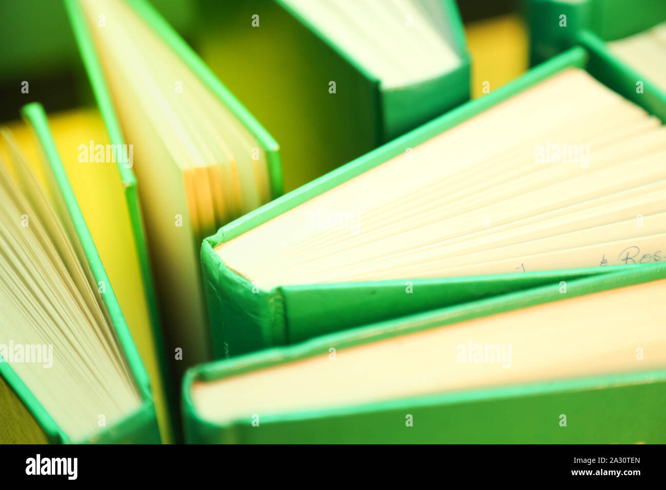 Green books on a yellow background - open pages Stock Photo - Alamy