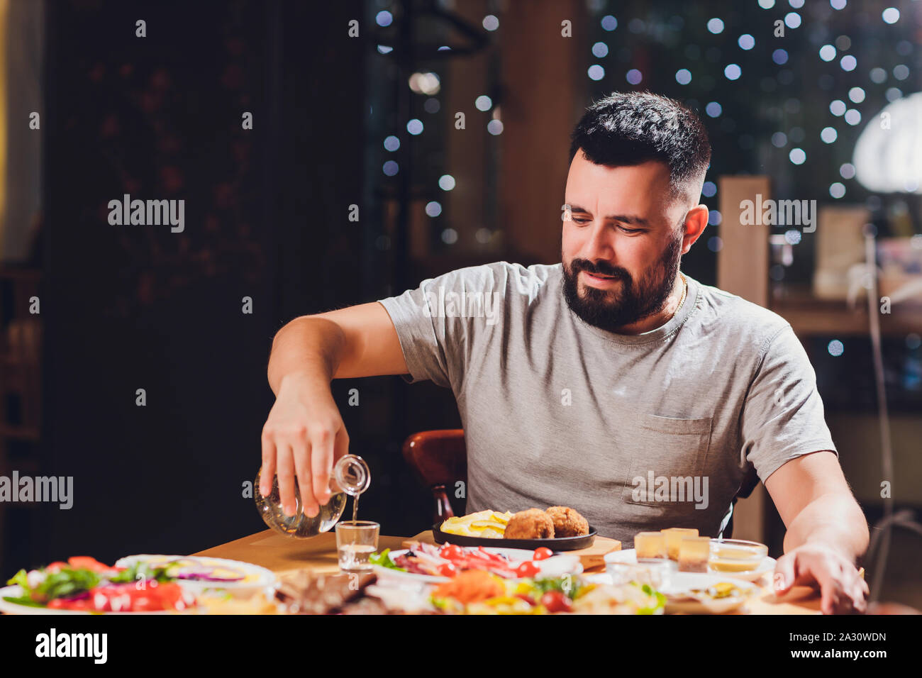 man drinks vodka at a large table with food and snacks Stock Photo - Alamy