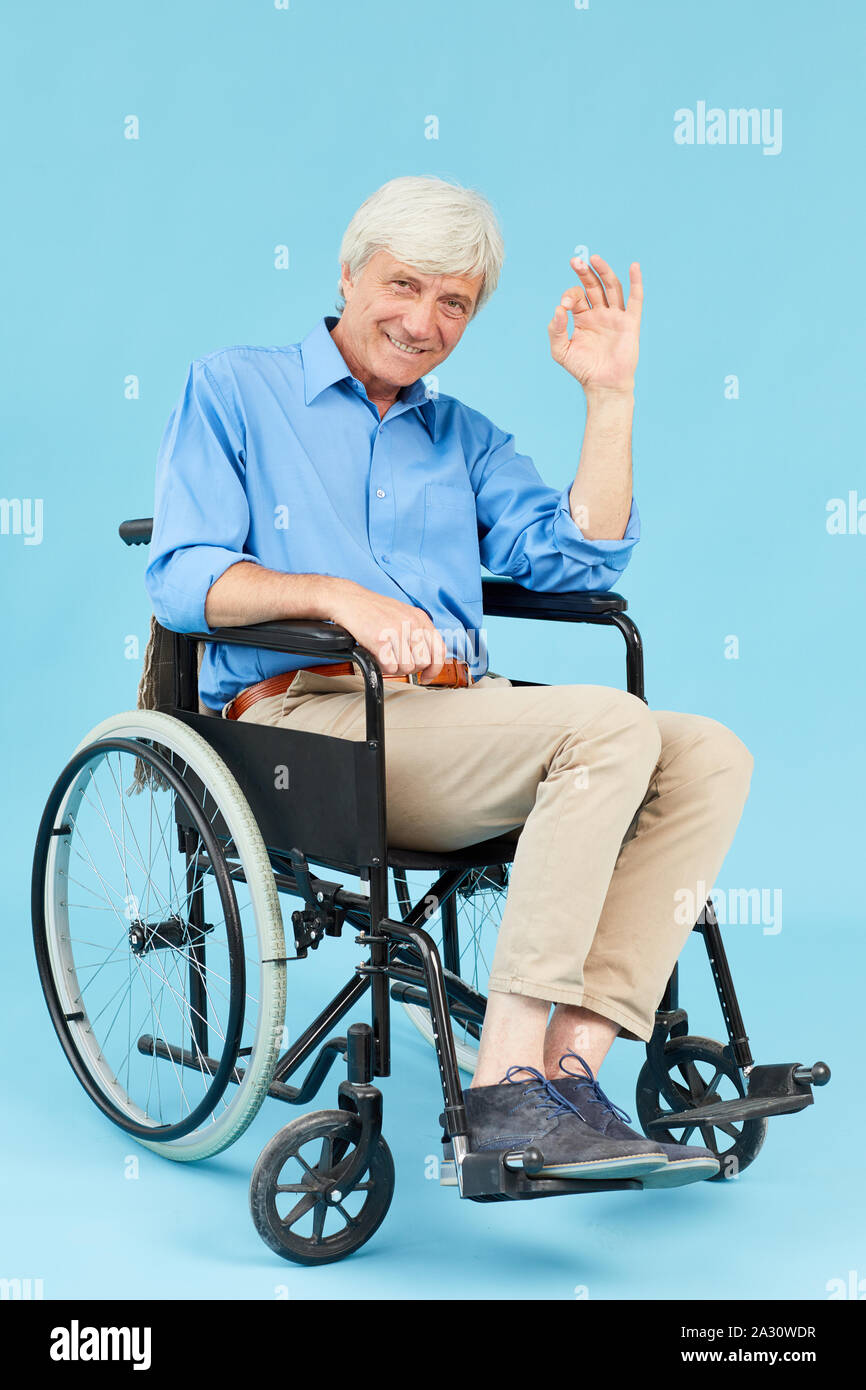Portrait of disabled senior man sitting in wheelchair showing OK sign ...