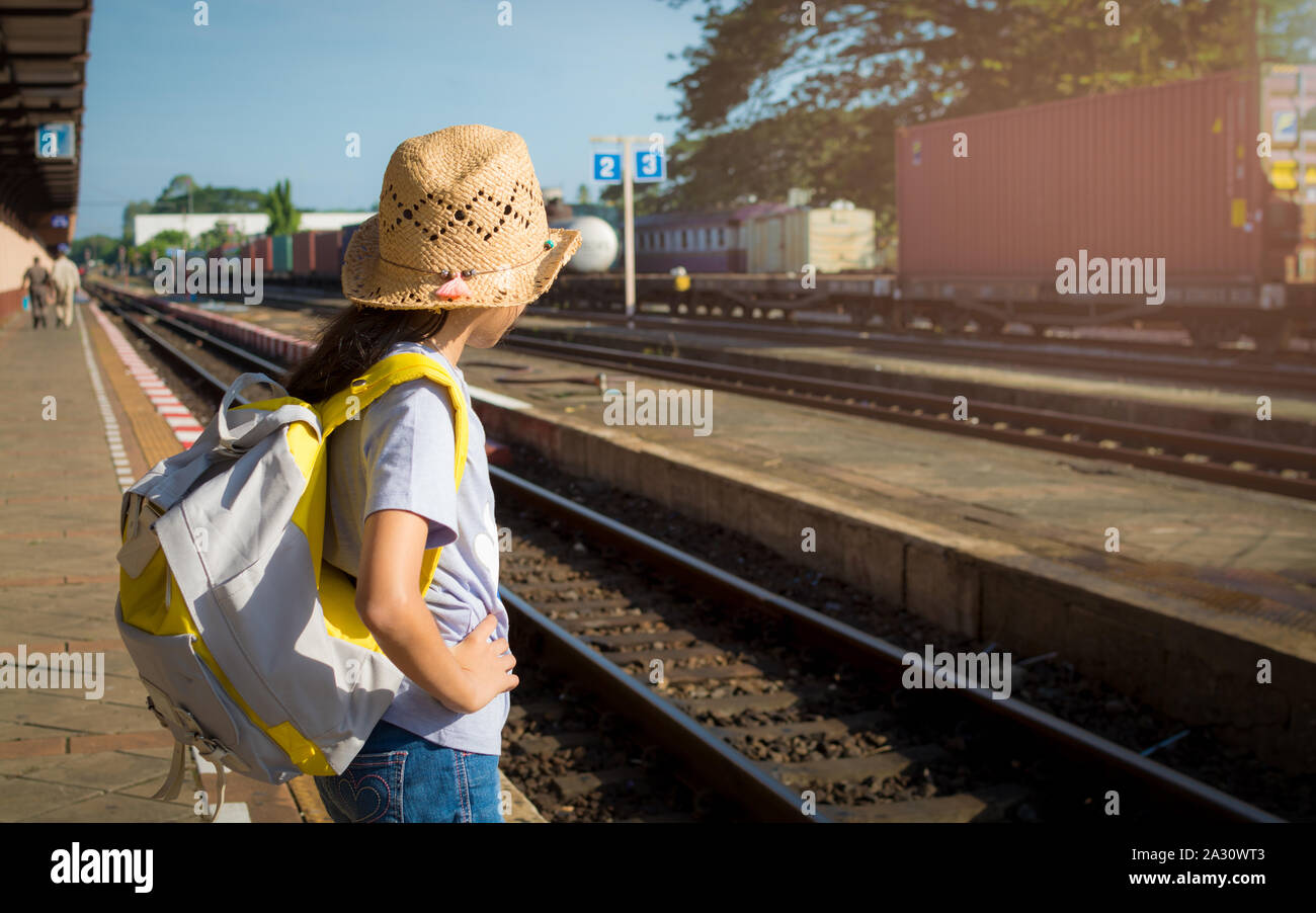 Young girl with bagpack waiting for a train at railway station in ...