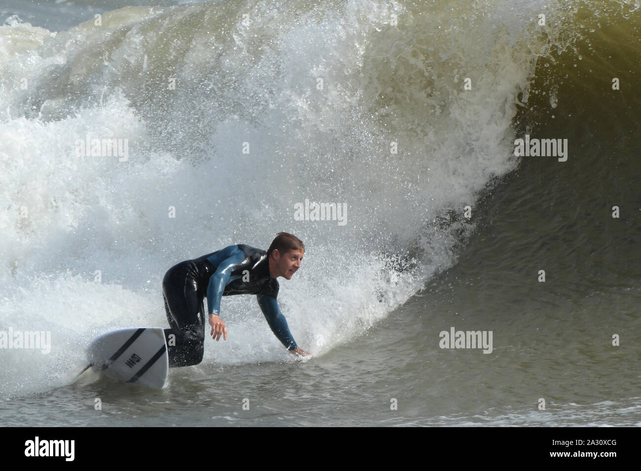Hand trailing in the wave, a surfer angles his surfboard and body into ...
