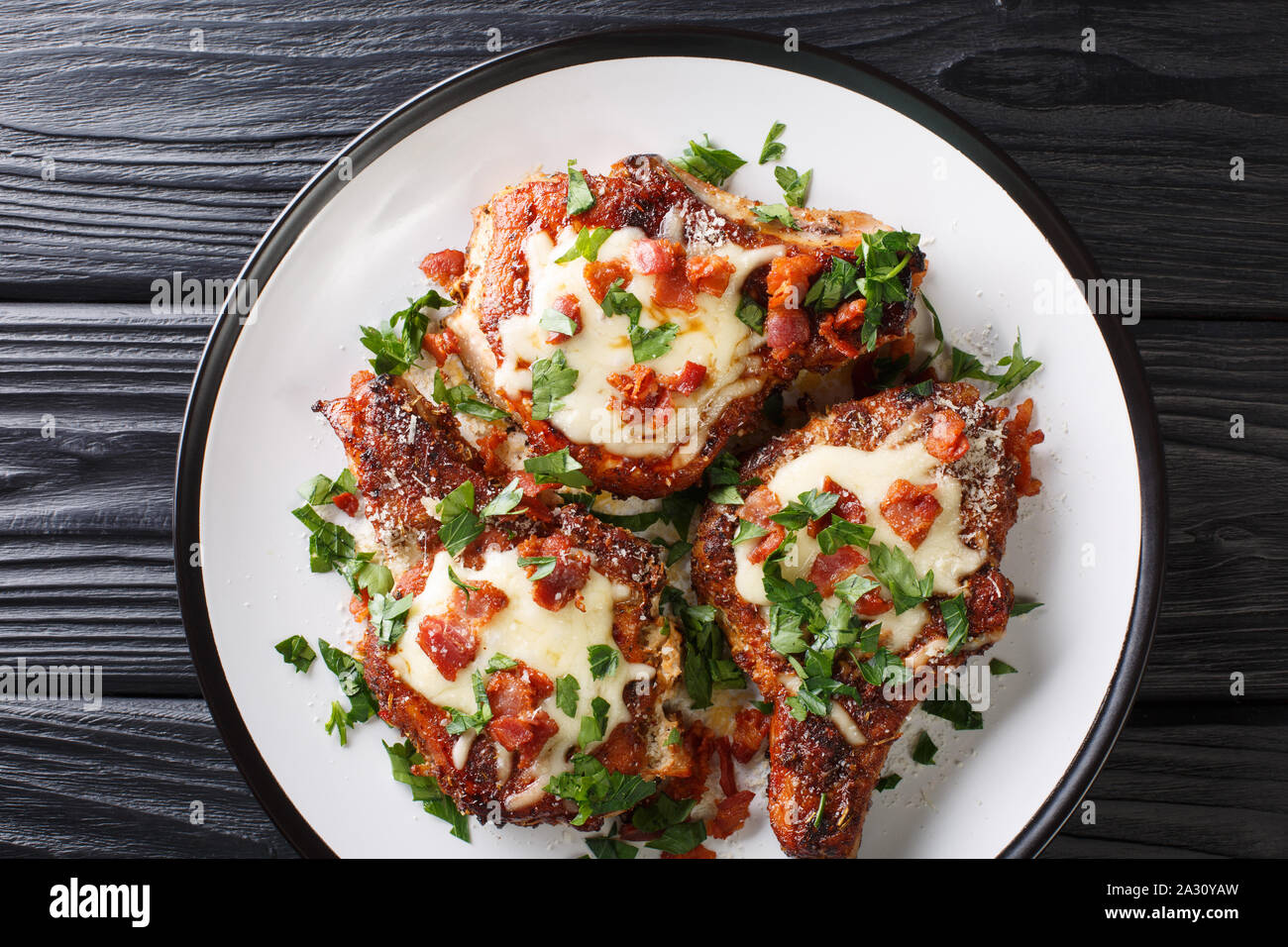Tasty pork chops with melted parmesan and bacon closeup on a plate on ...