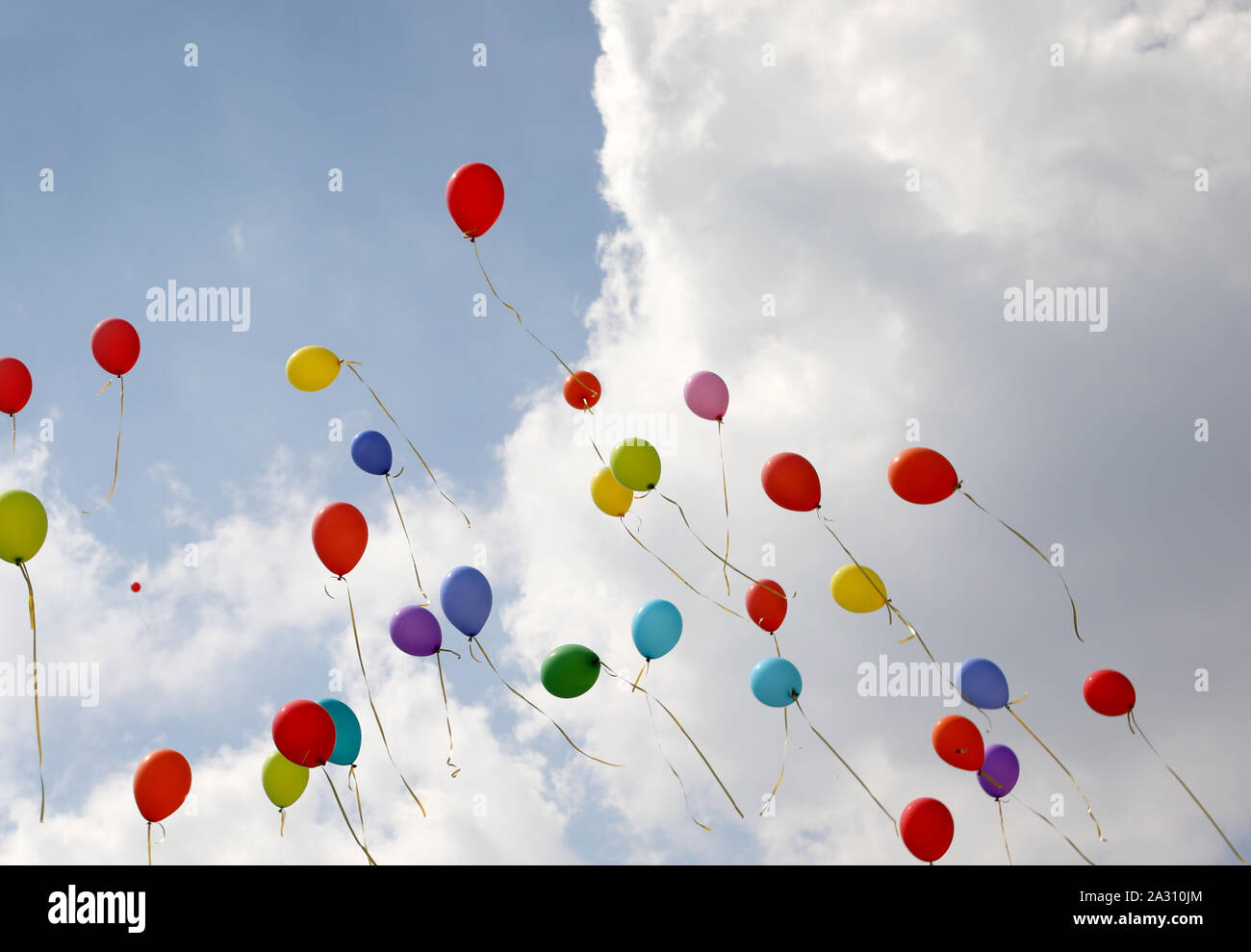 group of balloons fly into the blue sky with many white clouds in ...
