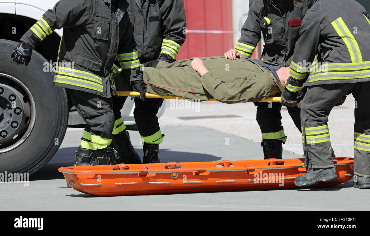 four firemen charge a wounded person on a stretcher after an accident ...