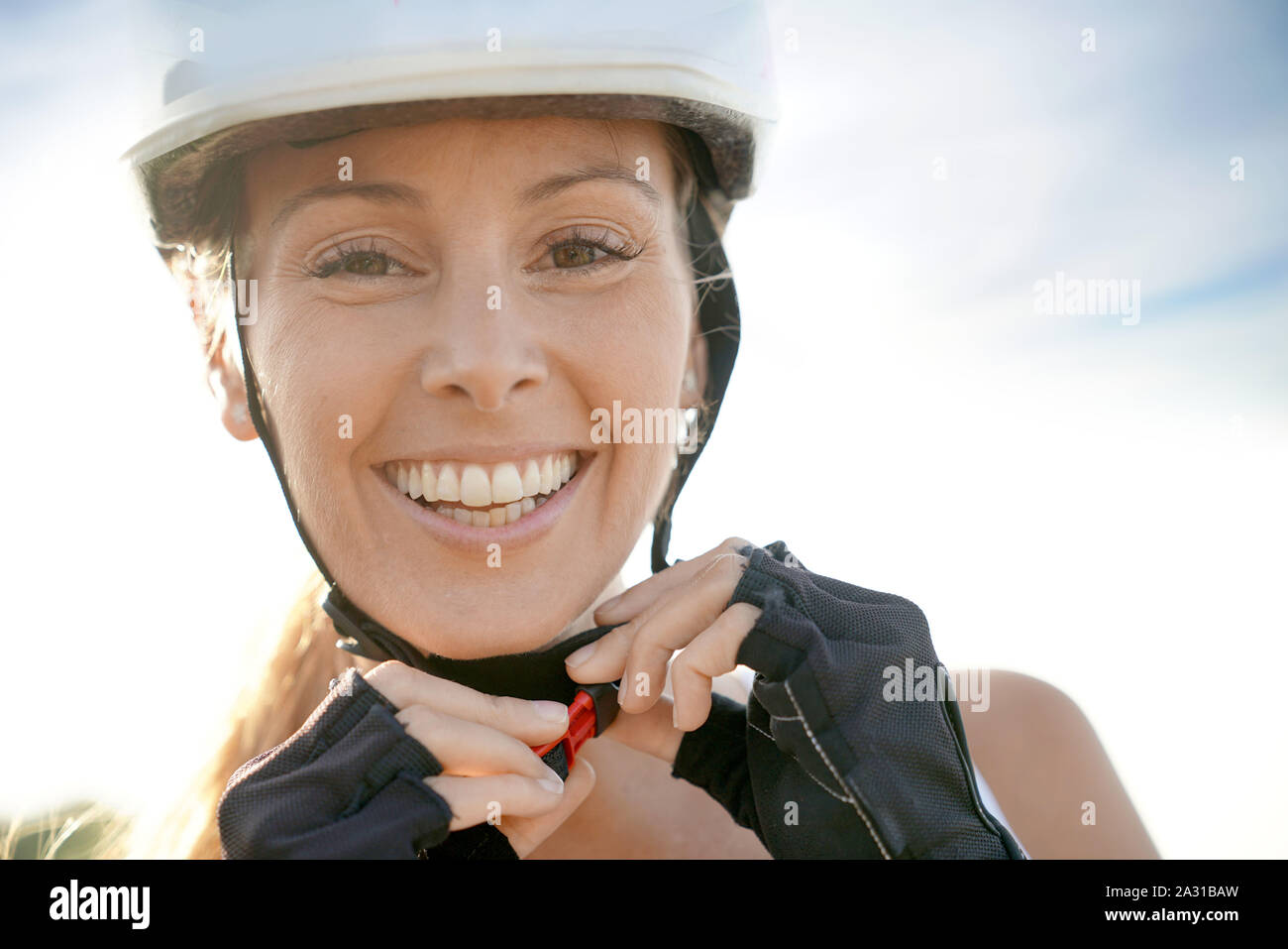 Portrait of smiling woman on bike ride putting helmet on Stock Photo ...