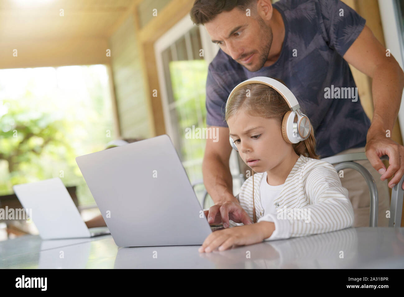 Little girl using laptop with help of daddy Stock Photo - Alamy