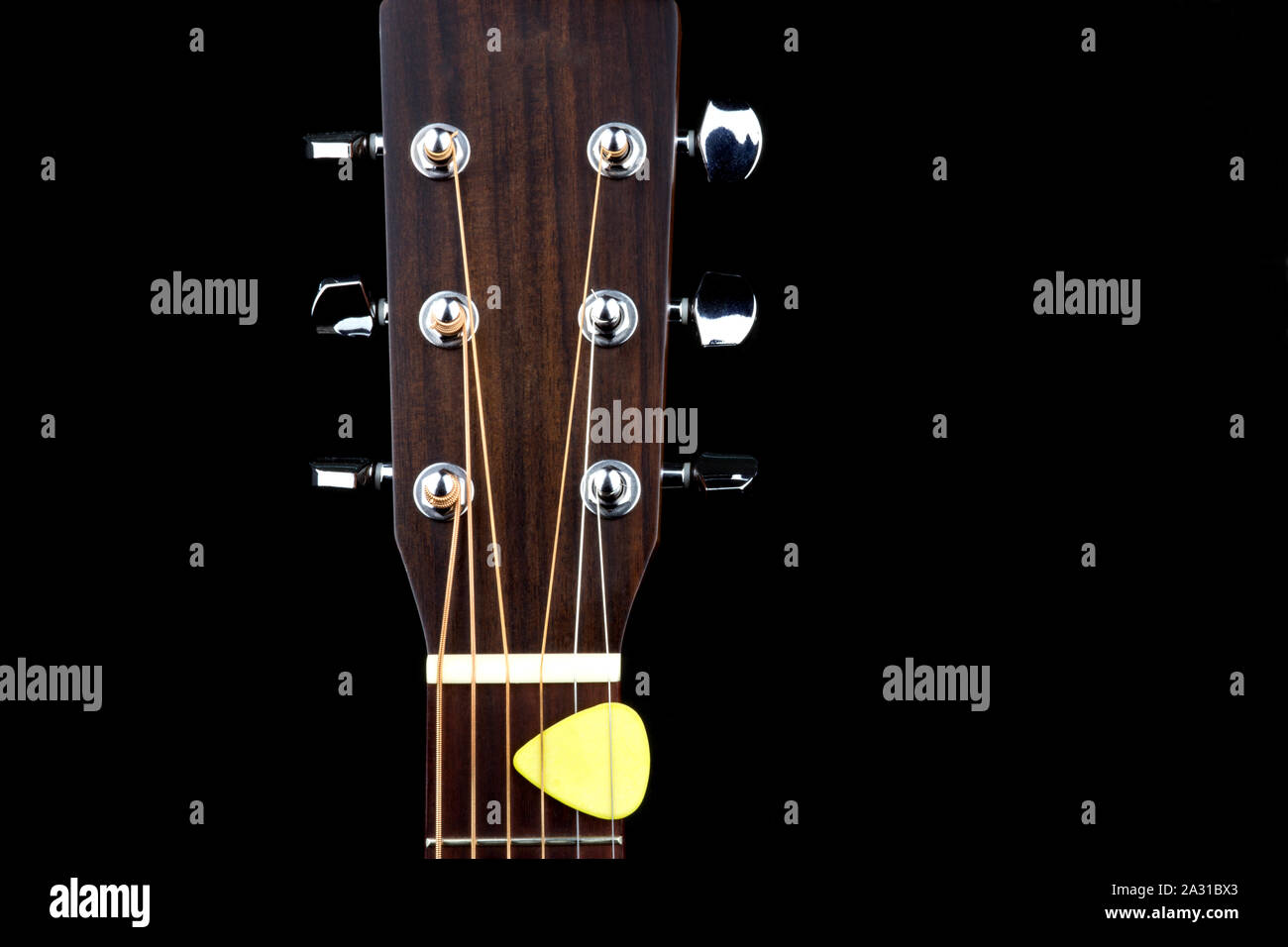 Acoustic guitar peg head and plectrum isolated on a black background ...