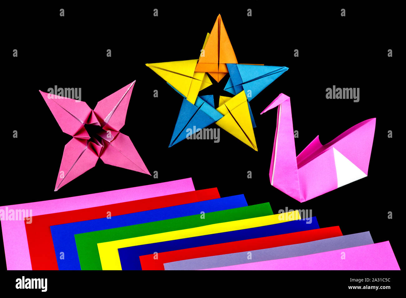 Paper origami models and coloured paper isolated against a black ...