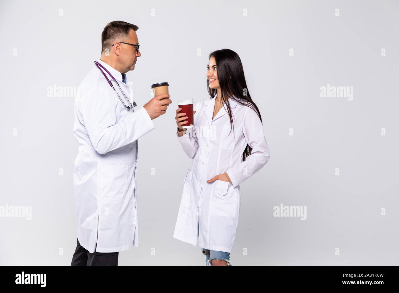 Beautiful young doctors are drinking coffee and smiling on white ...
