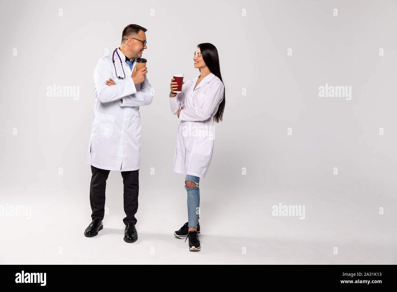 Beautiful young doctors are drinking coffee and smiling on white ...