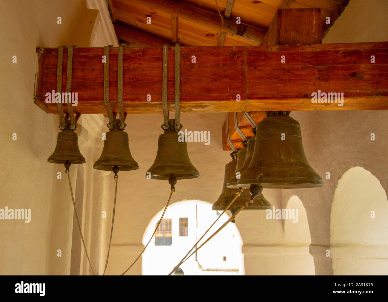 Bells of various sizes hang from a thick wooden beam Stock Photo - Alamy
