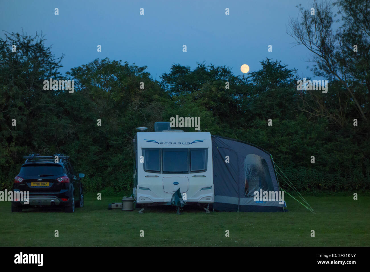 Touring caravan with awning attached at nighttime evening with a full ...