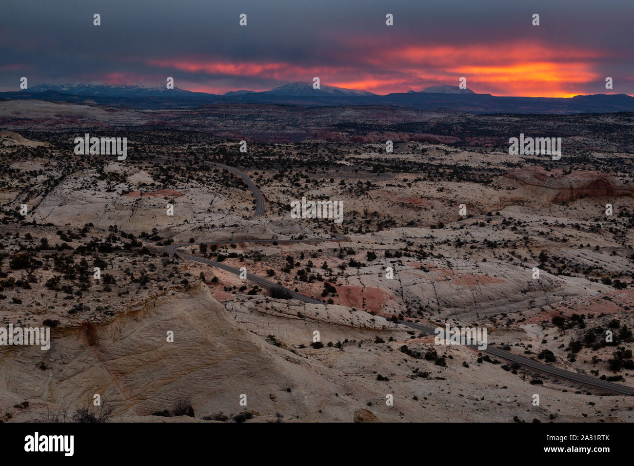 Highway 12 winding through sandstone dunes below a fiery sunrise and ...